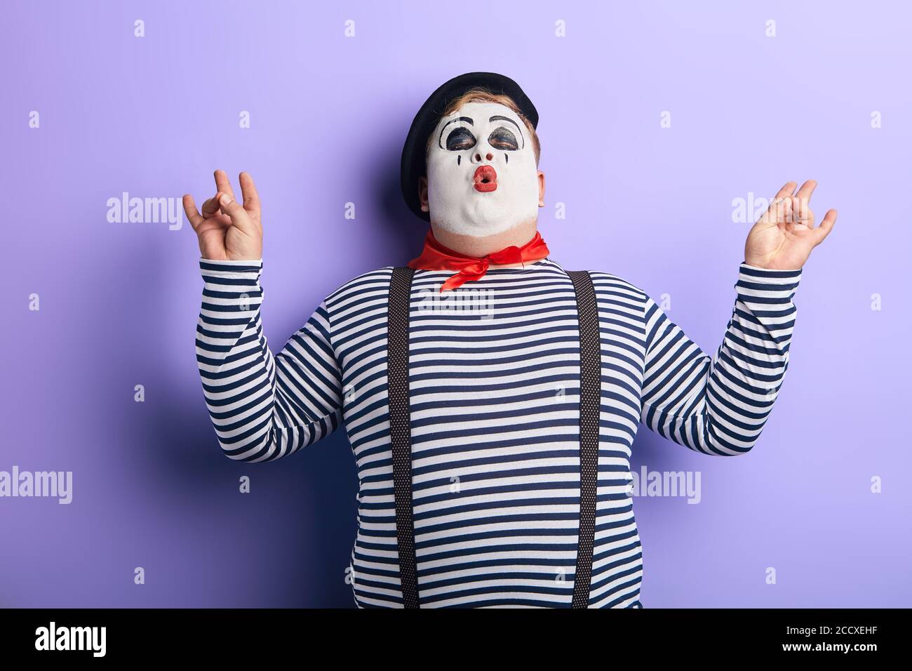 fat clown blowing his cheeks, doing yoga, reliefs stress. close up ...