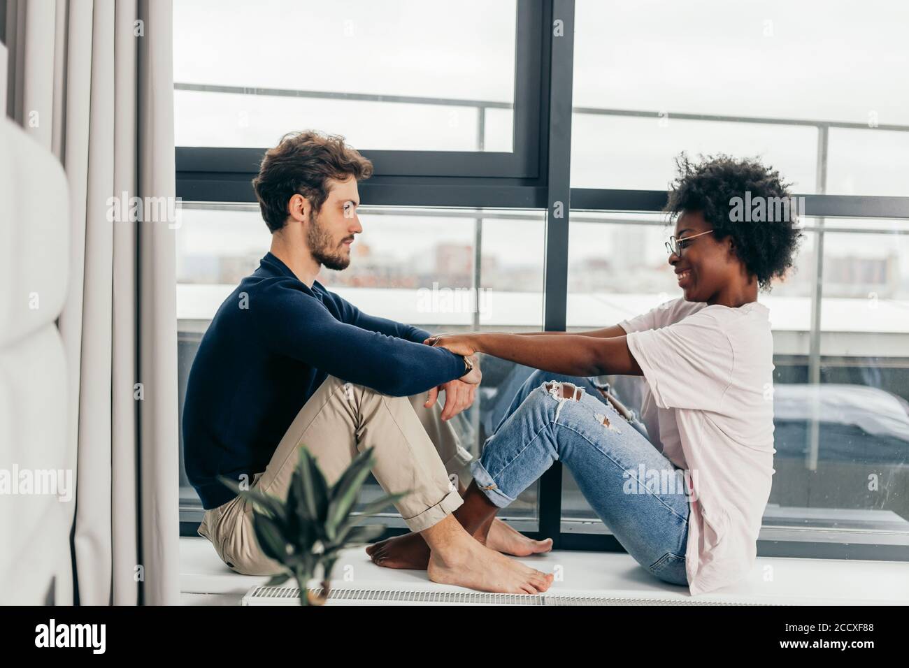 Romantic mixed race affectionate young newlyweds relax at modern hotel ...