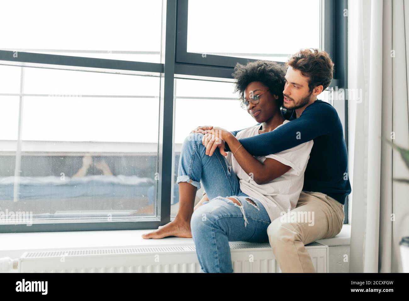 Romantic mixed race affectionate young newlyweds relax at modern hotel ...