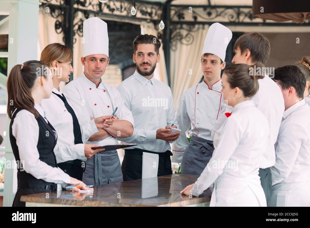 Restaurant manager and his staff in terrace. interacting to head chef ...