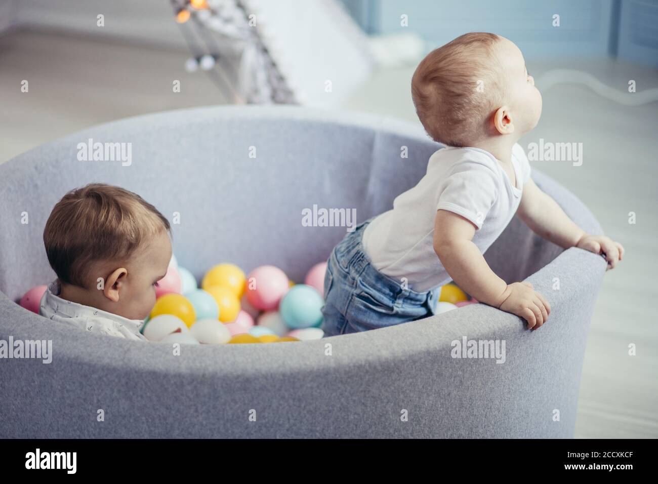 Two happy cute one year old infant boys are playing with colourful ...