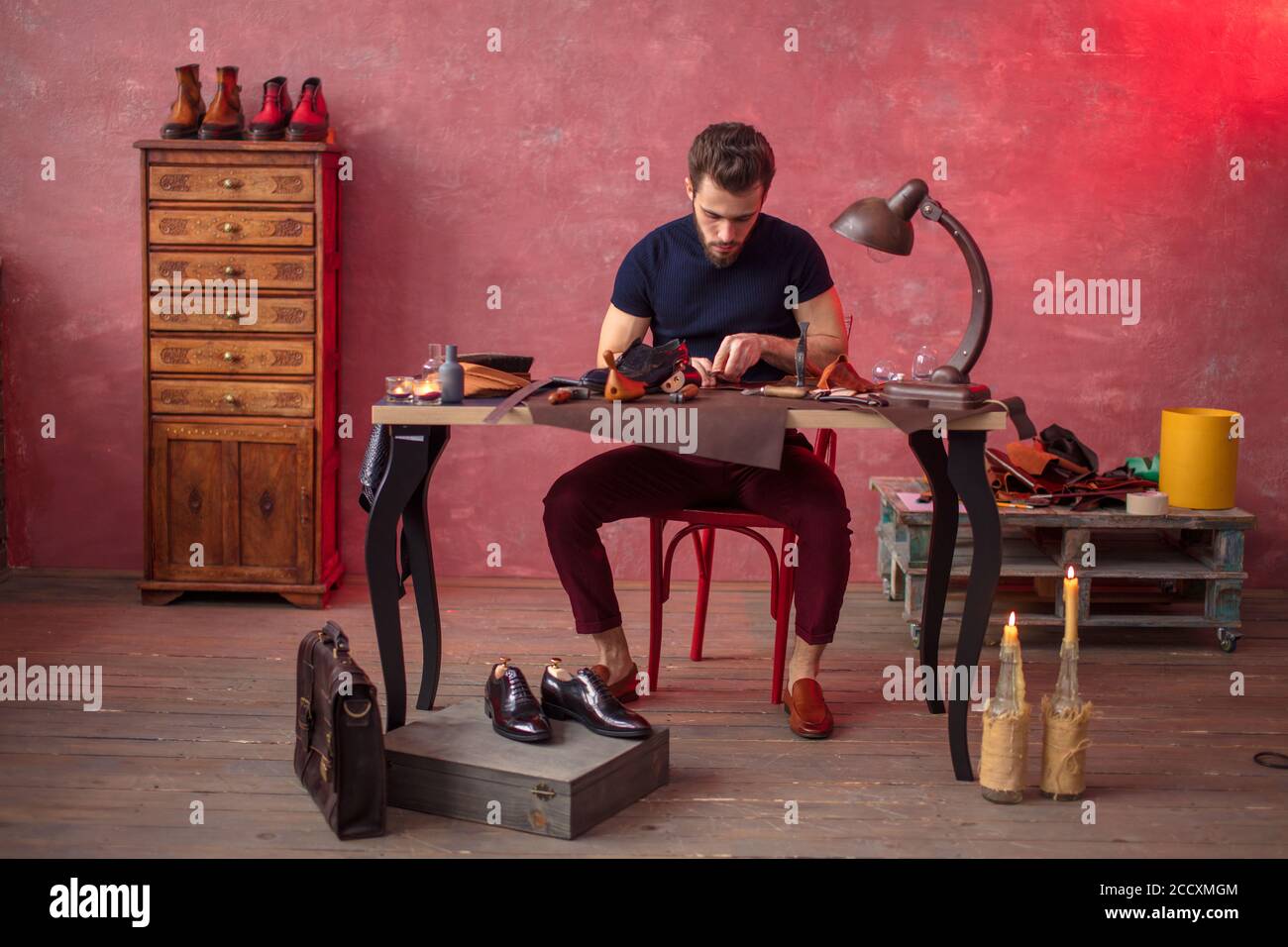 serious shoemaker reparing shoes while sitting at the table. full ...