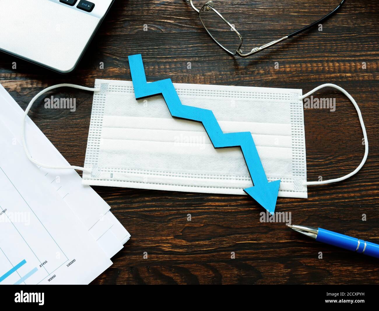 Medical mask and down arrow as symbol of decrease of economy or number ...