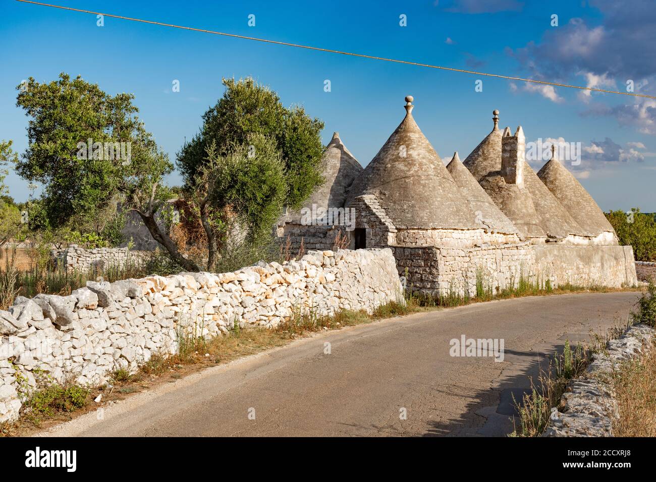 Group of beautiful Trulli, traditional old houses and old stone wall in ...