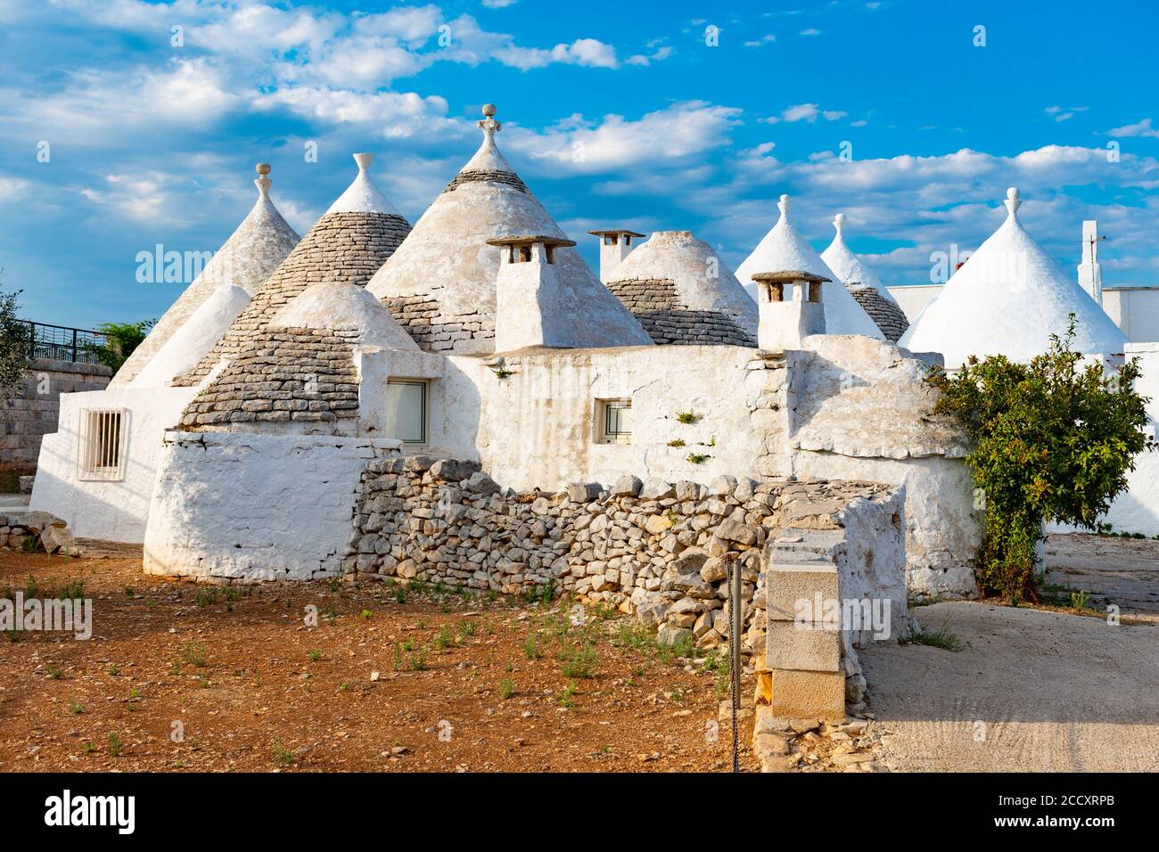 Group of beautiful Trulli, traditional old houses and old stone wall in ...