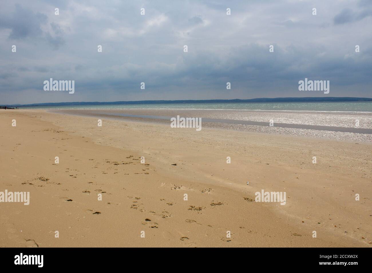 Empty beach with dark clouds overhead Stock Photo - Alamy