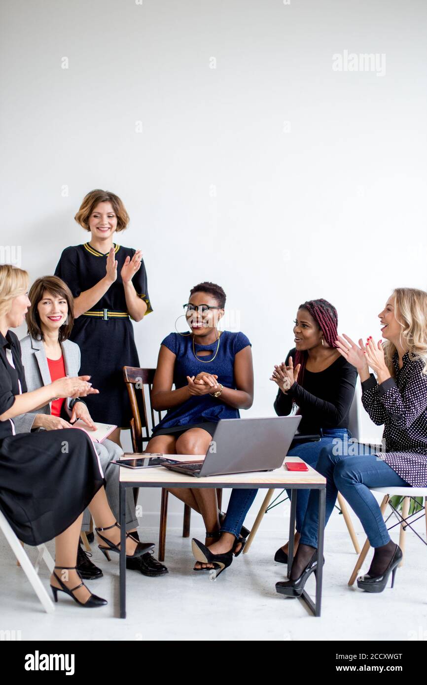 Crew of multiracial female co-workers watching video on netbook for new ...