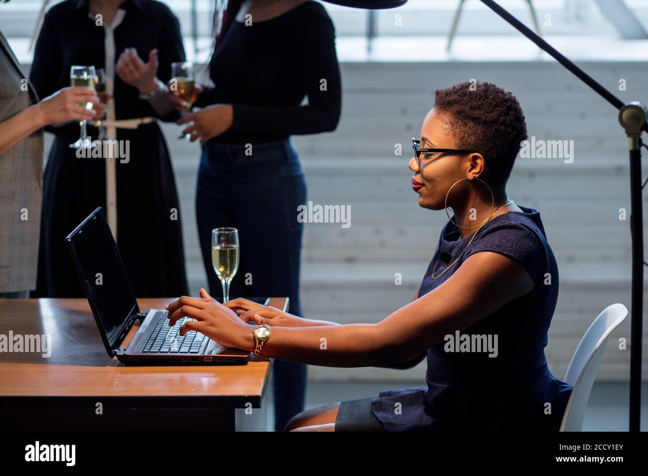 Side view of young african female co-worker sitting at the table, woman ...