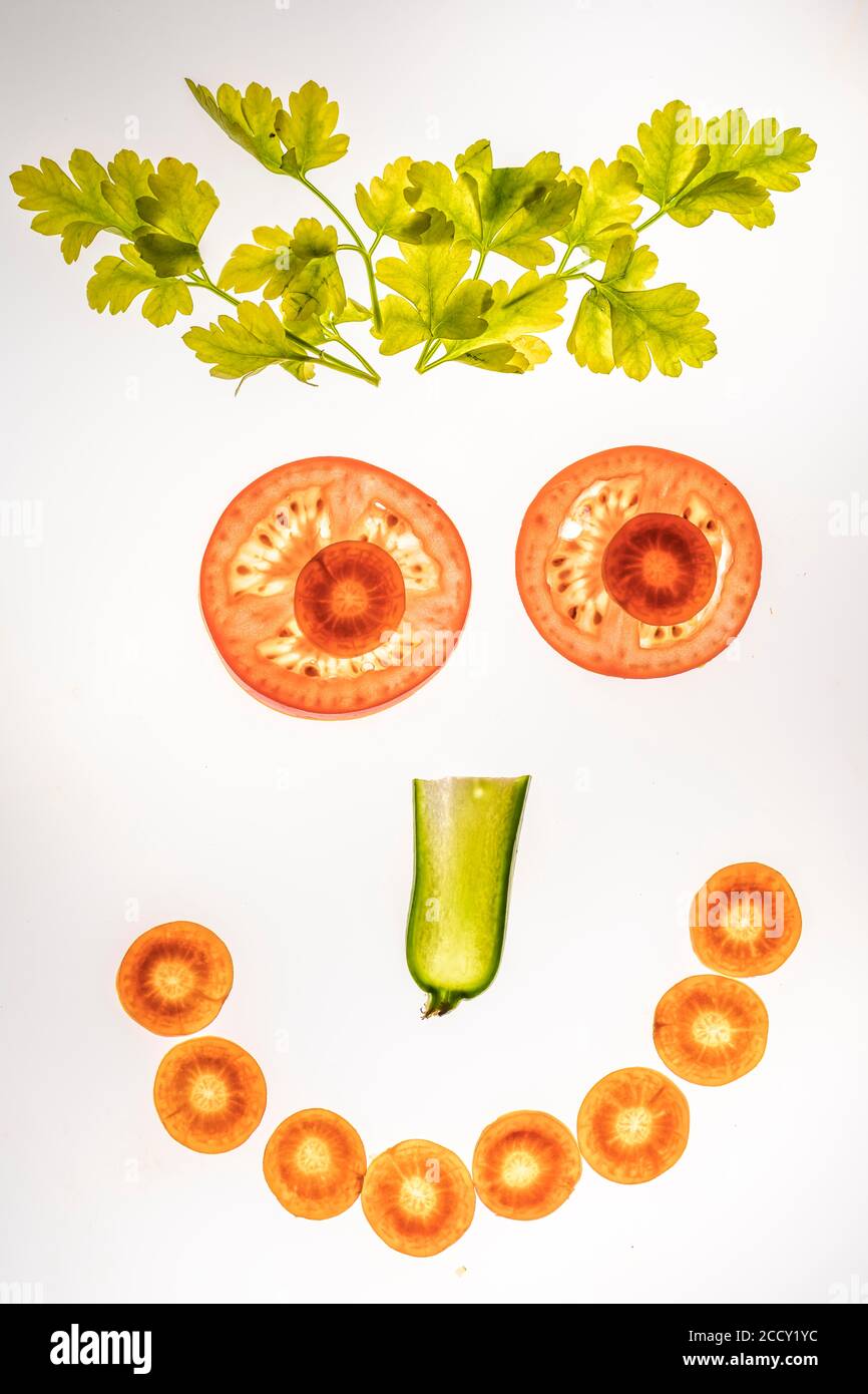 Laughing face of vegetables, smiley face, slices of cucumber, carrot and tomato with parsley ...