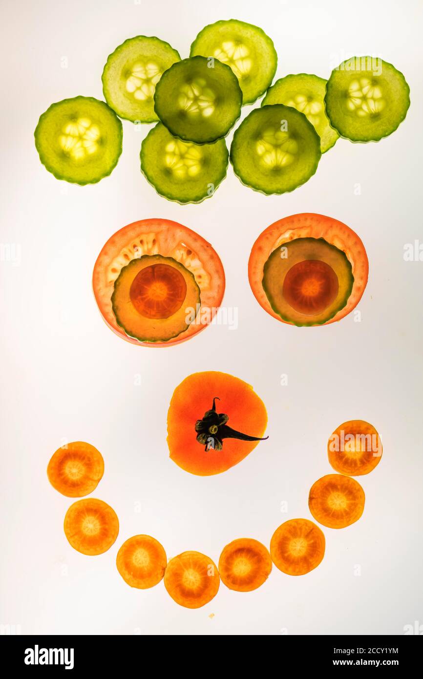 Laughing face of vegetables, smiley face, slices of cucumber, carrot and tomato, white ...
