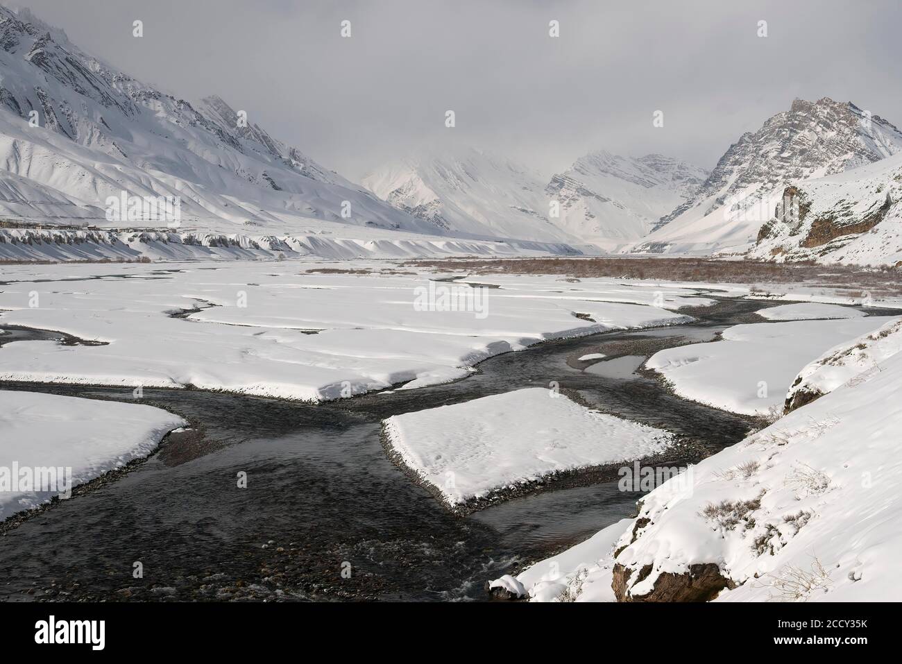 River flowing through snow covered mountains in Spiti, a high altitude ...