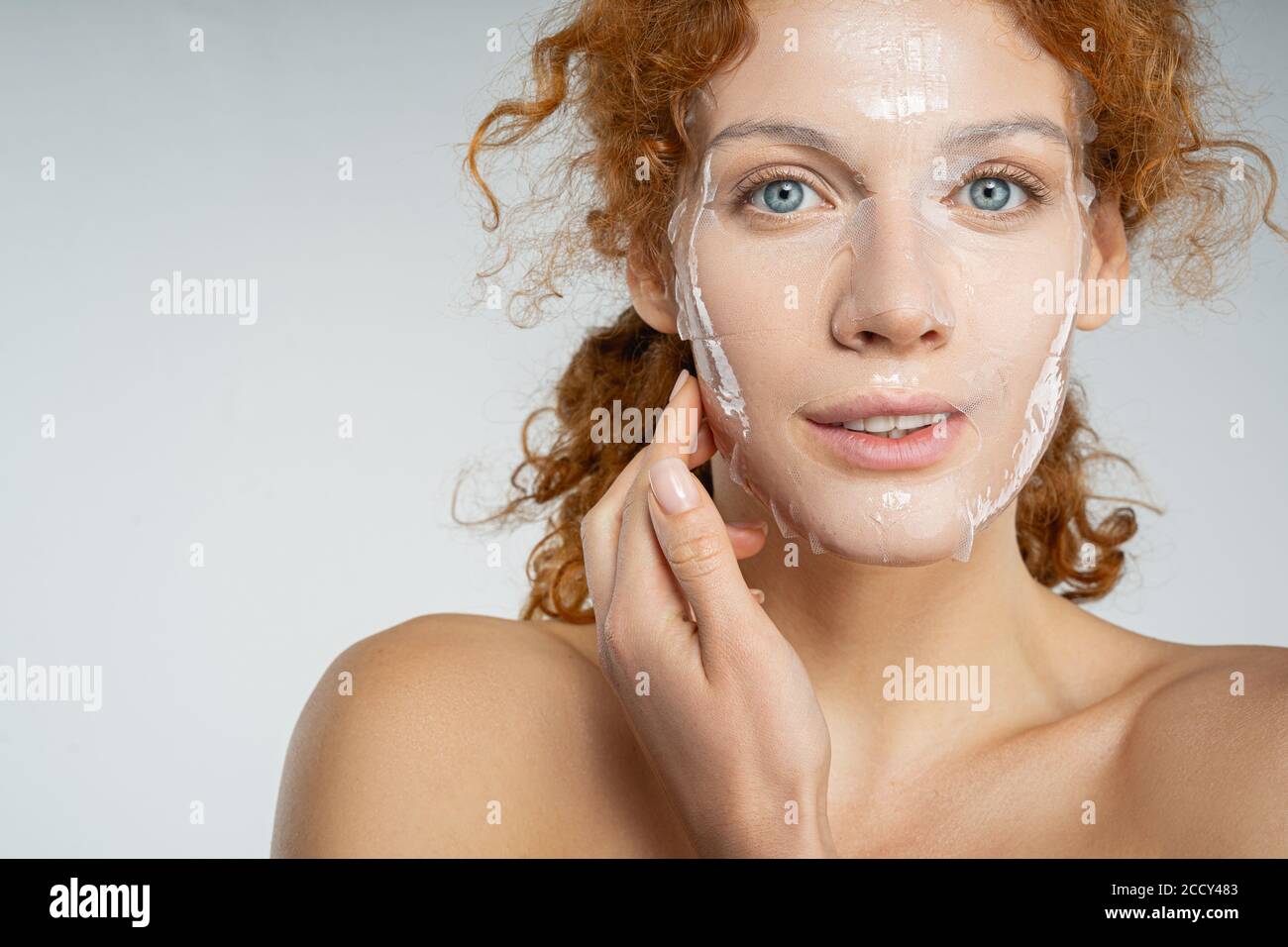 Lovely red-headed female wearing a sheet mask Stock Photo - Alamy