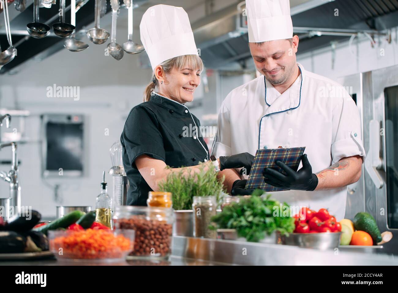 Two chefs discuss the menu in the kitchen of a restaurant or hotel ...