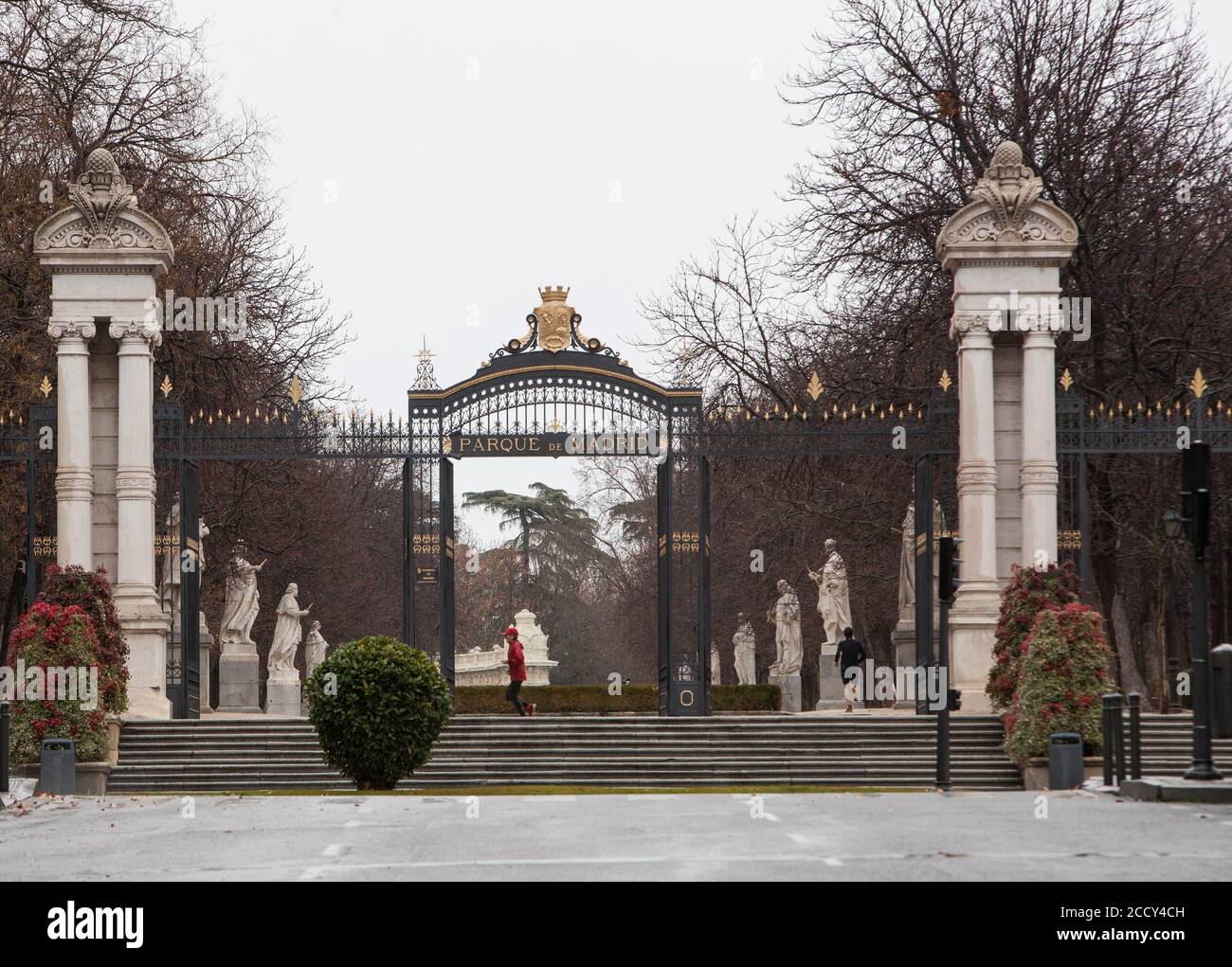 Two runners at the entrance of the Retiro Park on a rainy day in Madrid ...