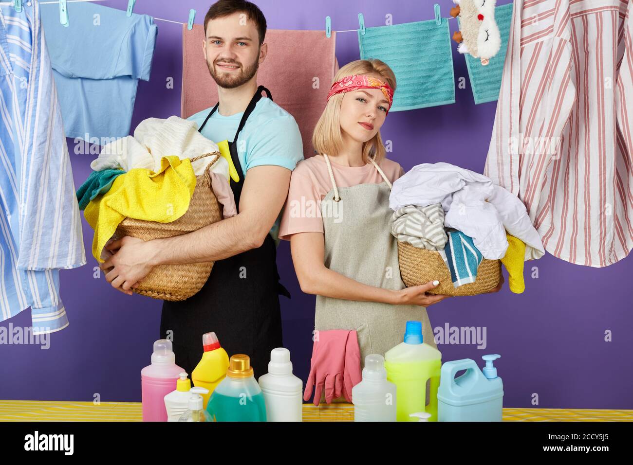 hardworking attractive couple holding basket of laundry and looking ...