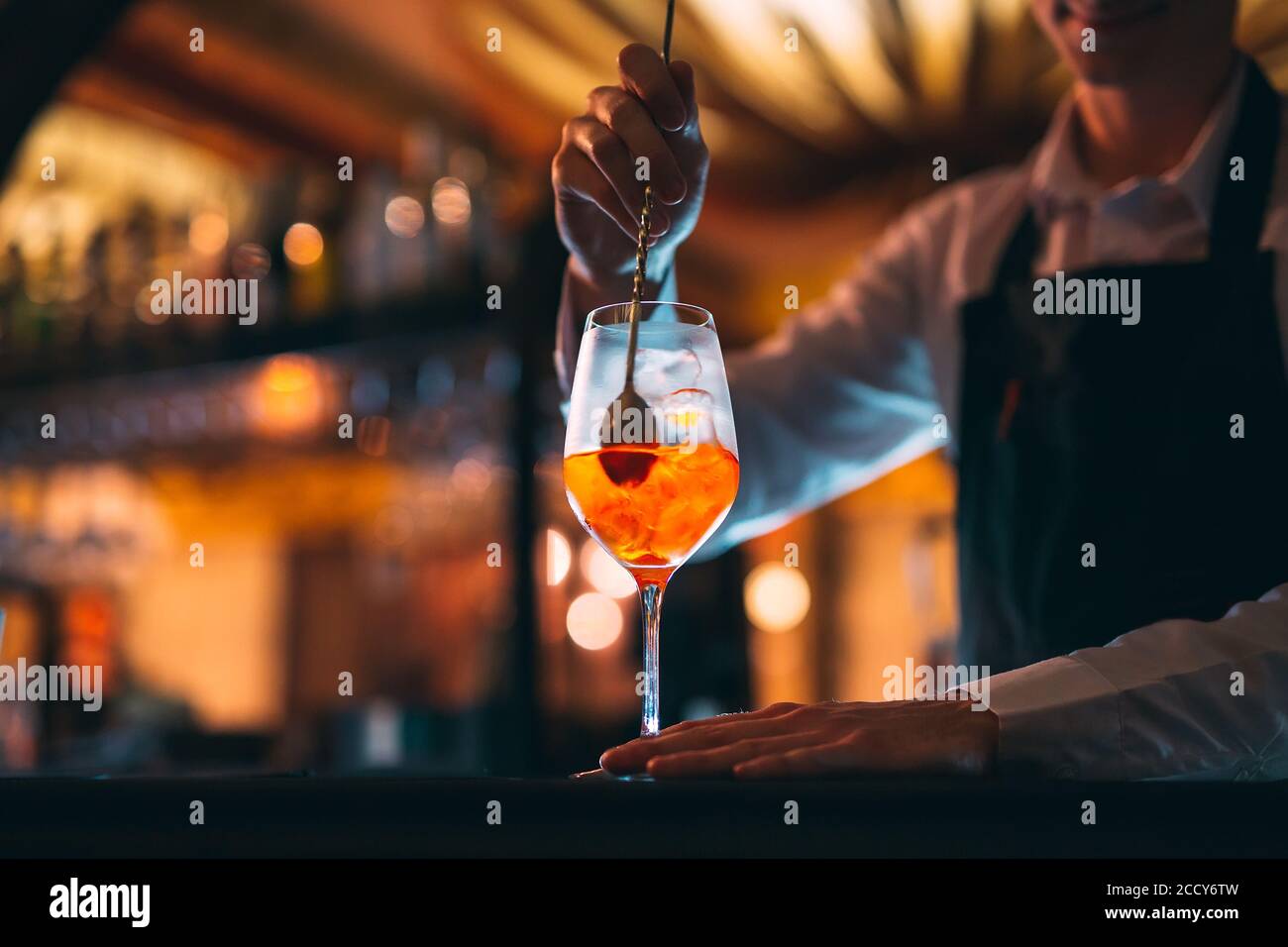 Barman hand stirring a fresh and sweet orange summer cocktail with a ...