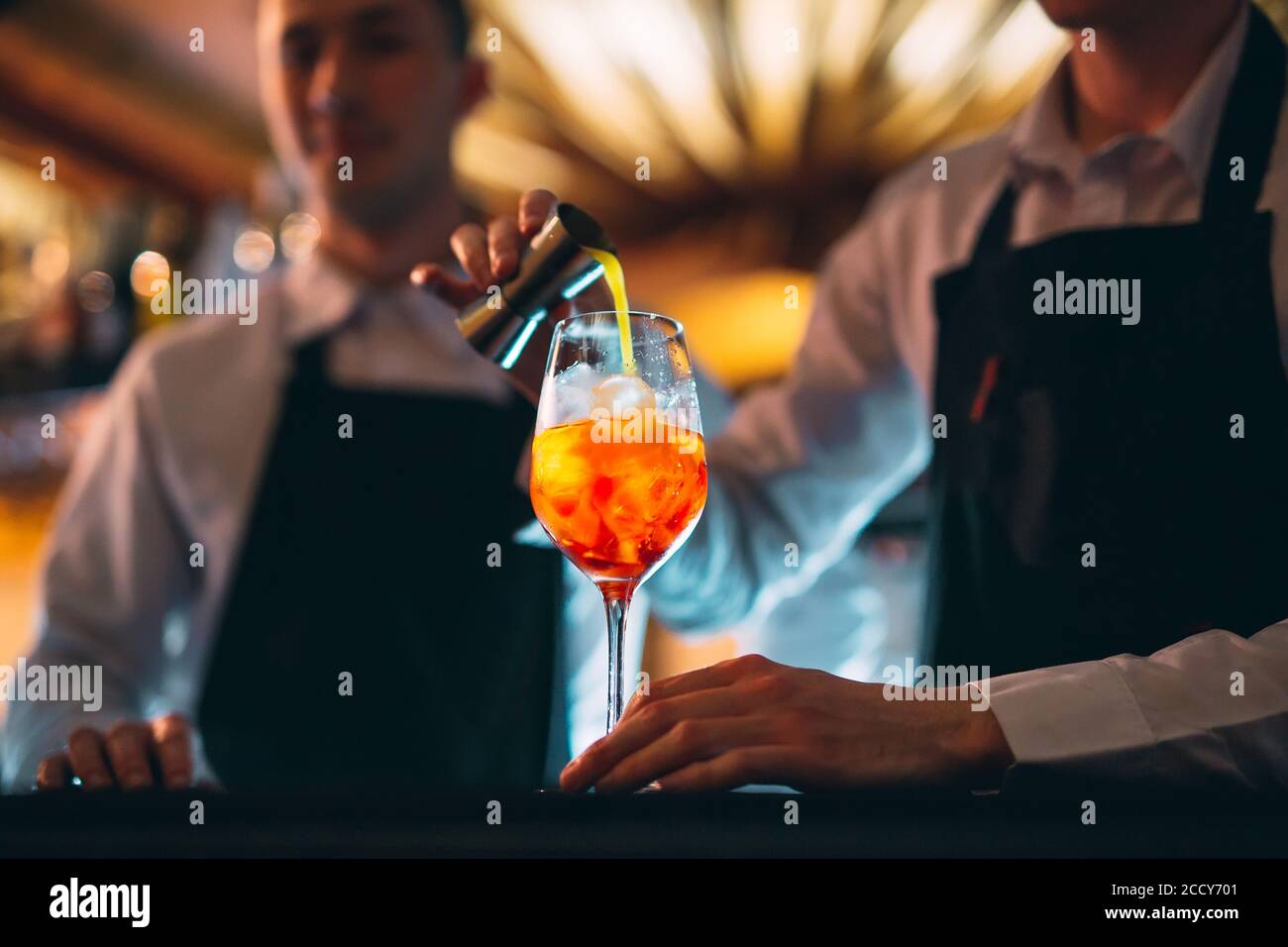 Barman hand stirring a fresh and sweet orange summer cocktail with a ...