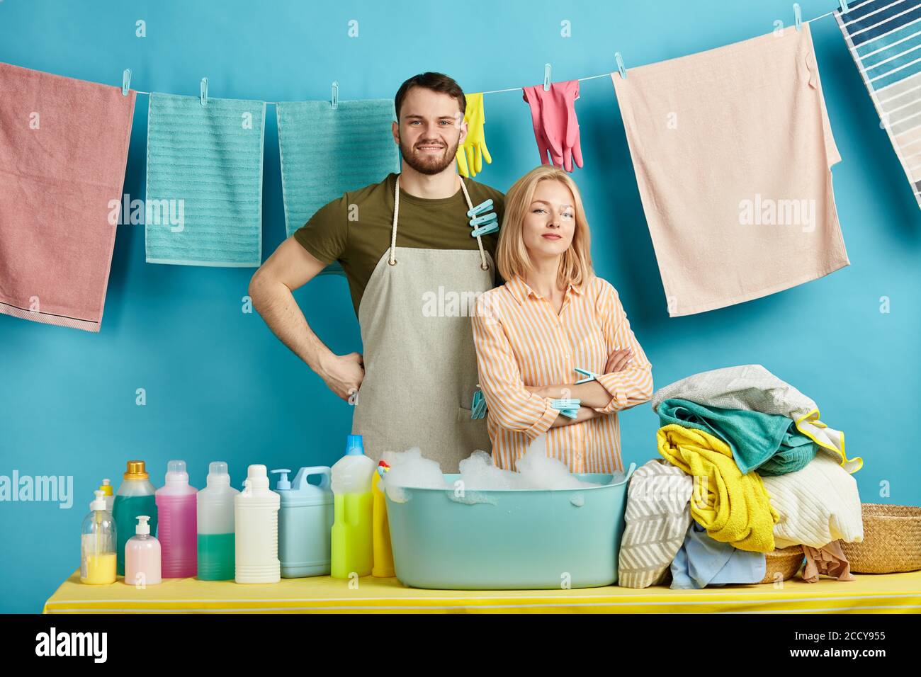 smiling positive hardworking couple ready to help you with laundry ...