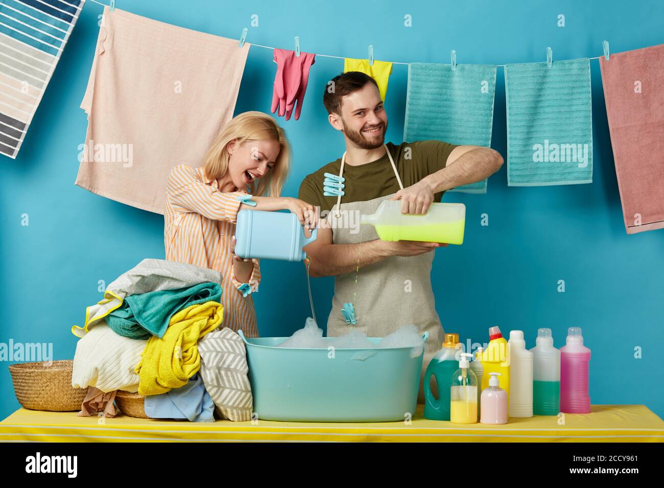 young hardworking couple enjoying washing clothes, expressing positive ...