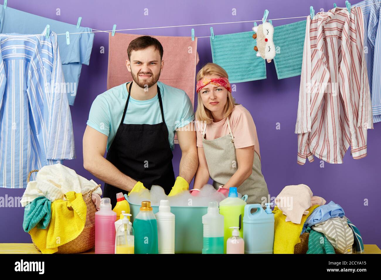 young couple don't want to do household chores. studio shot. isolated ...