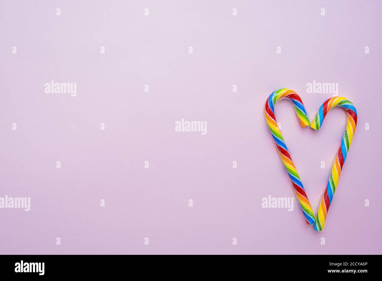 white and red candy canes in the form of a heart on a pink background ...