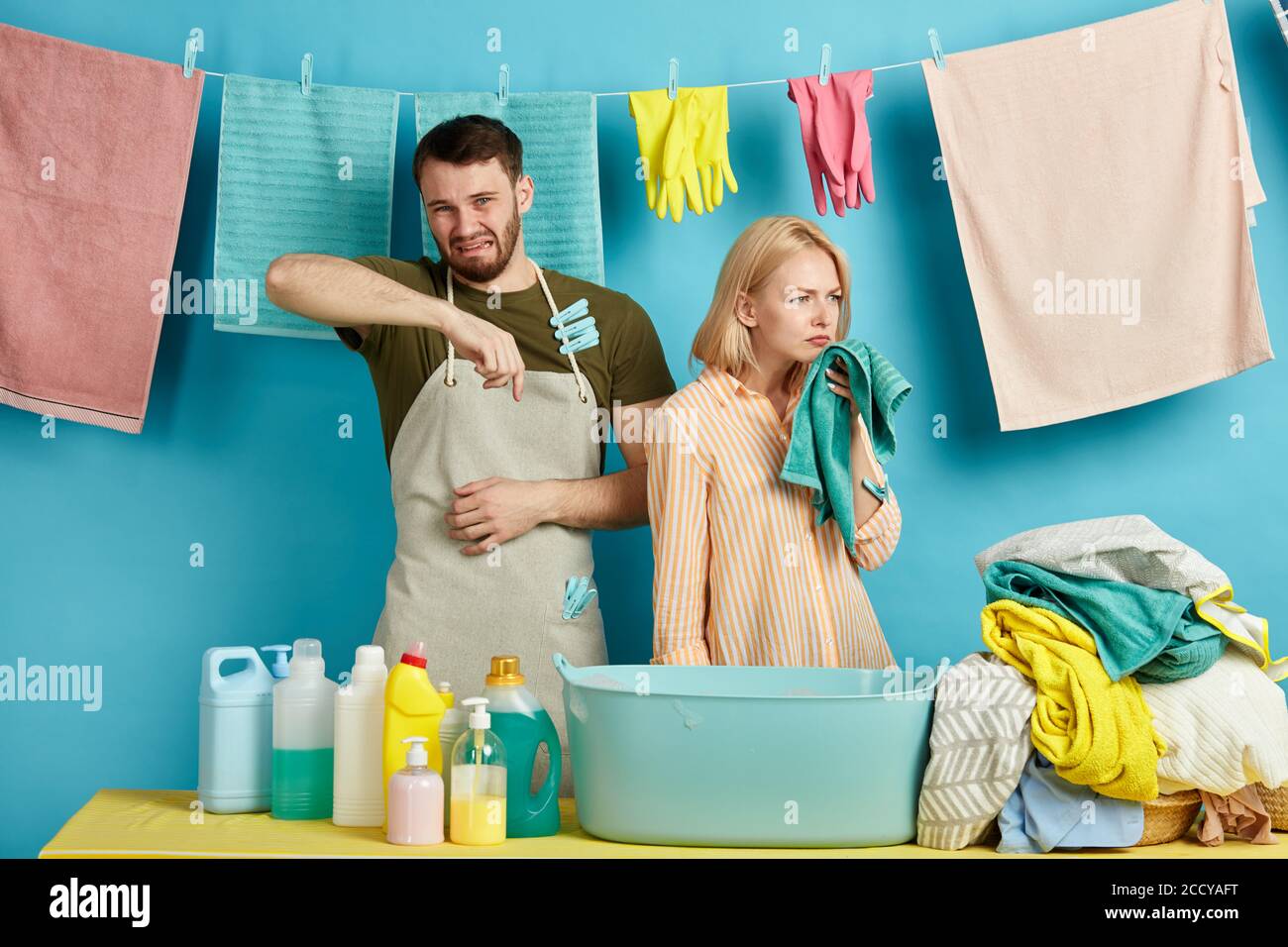 unhappy sad young man and woman in aprons are allergic to washing ...