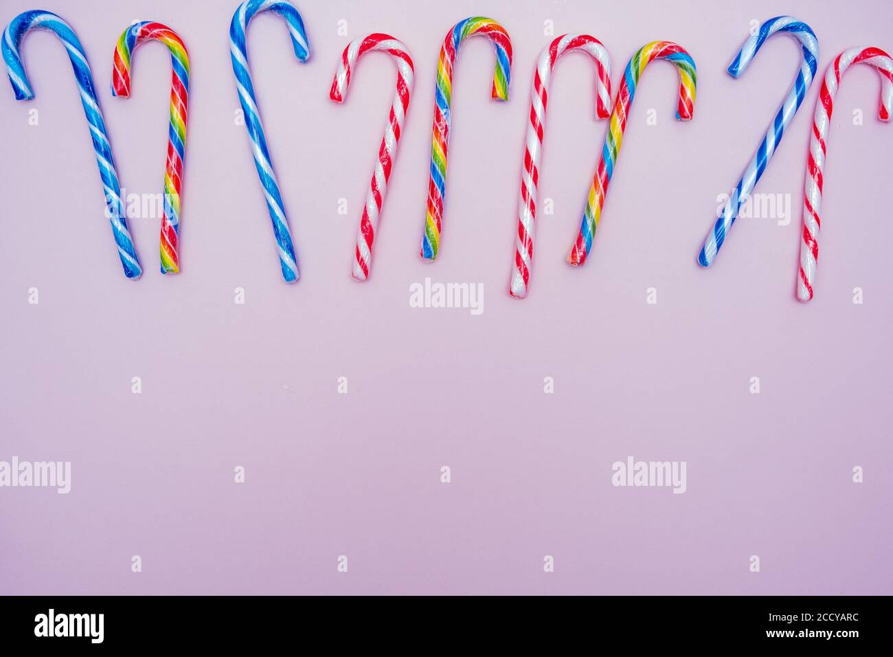 lot of multi-colored candy canes on a pink background, copy space Stock ...