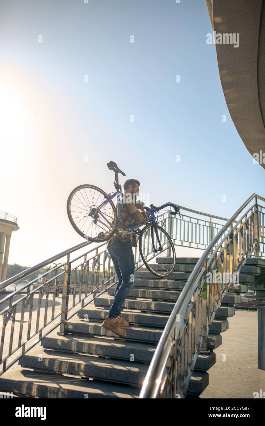 Young man carrying bicycle up the steps Stock Photo - Alamy
