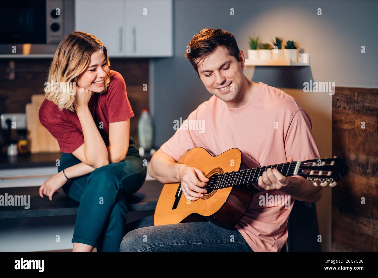 two friends sit playing the guitar, relax and enjoy performing music ...