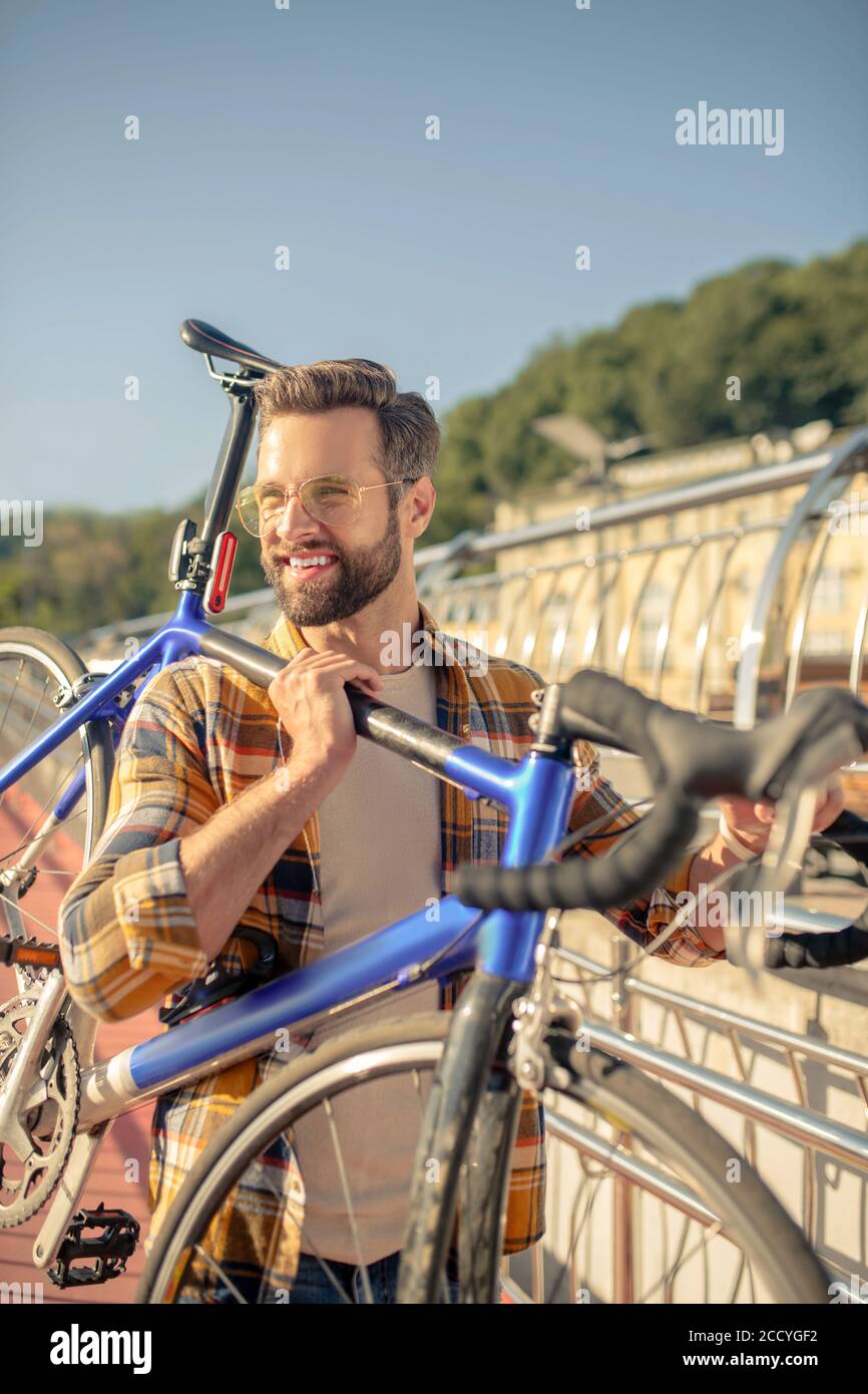 Man standing on street holding bicycle on his shoulder Stock Photo - Alamy
