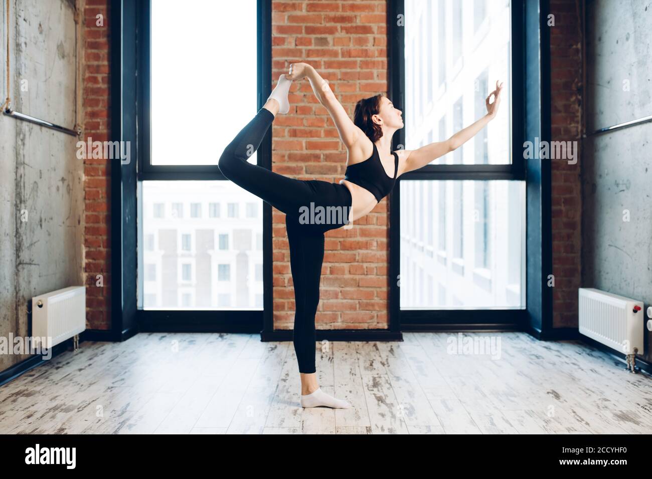 Sporty young flexible woman doing yoga standing split exercise in the ...