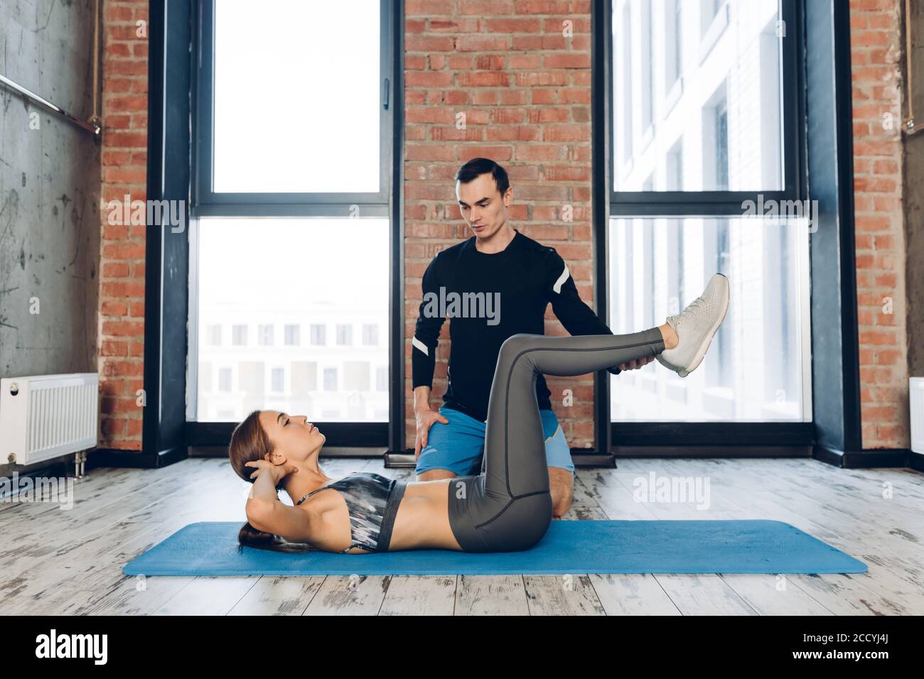 a muscularwoman doing abdominal exercise while personal trainer ...