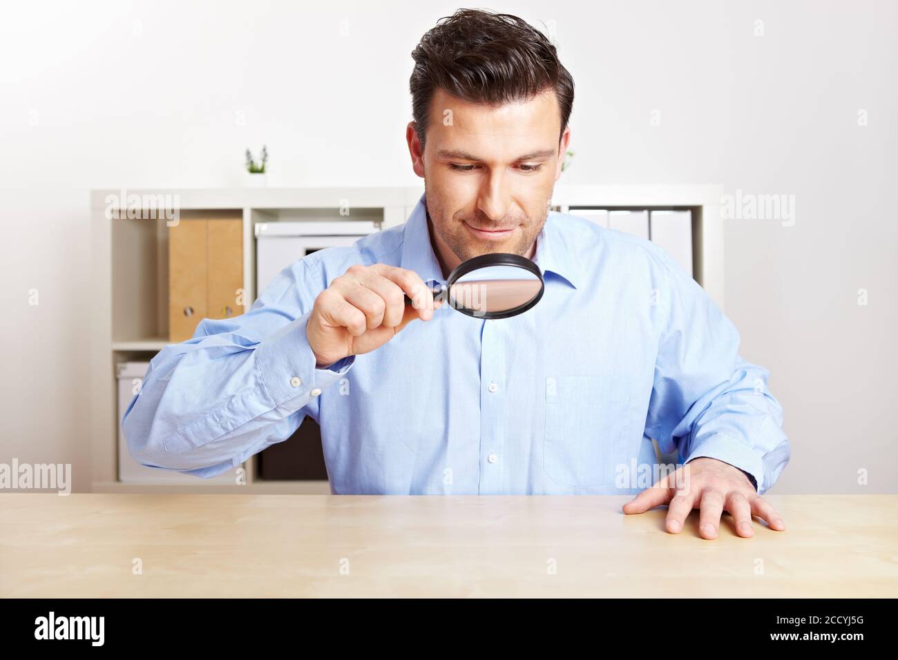 Businessman looks with a magnifying glass at an empty table in the ...