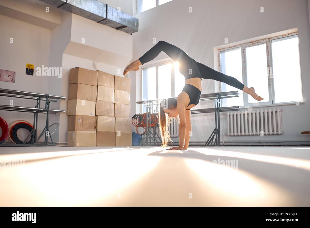 Young full of energy girl making hand standing pose, doing splits in ...