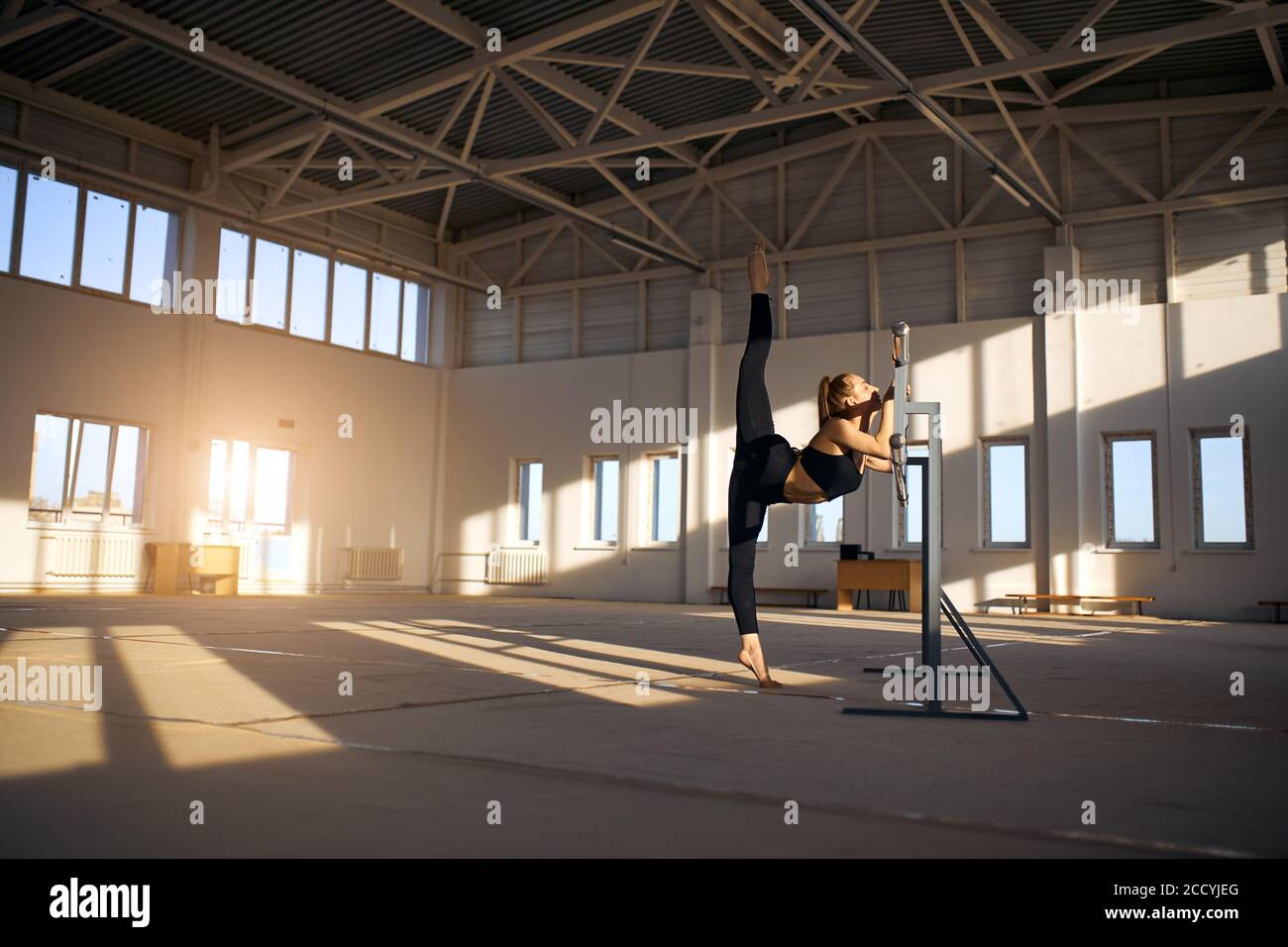Charming young female acrobat practicing in gymnasium, doing splits in ...