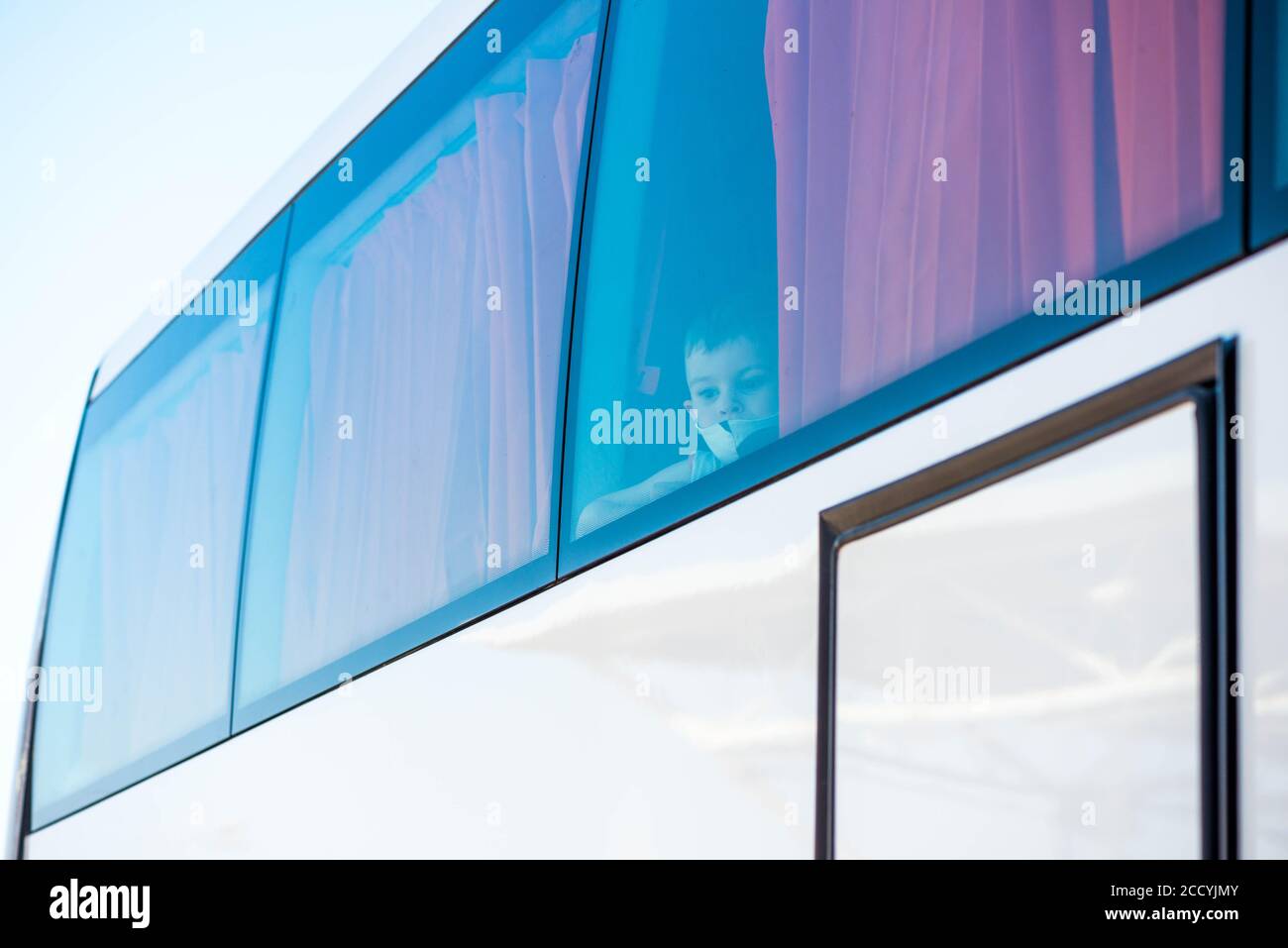 boy in protective mask looking out from tourist buss window Stock Photo ...