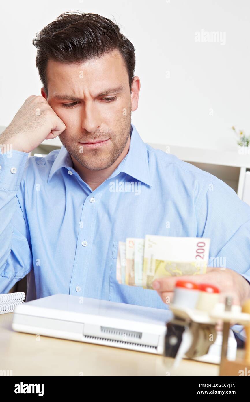 Worried man in the office looks at euro notes Stock Photo - Alamy