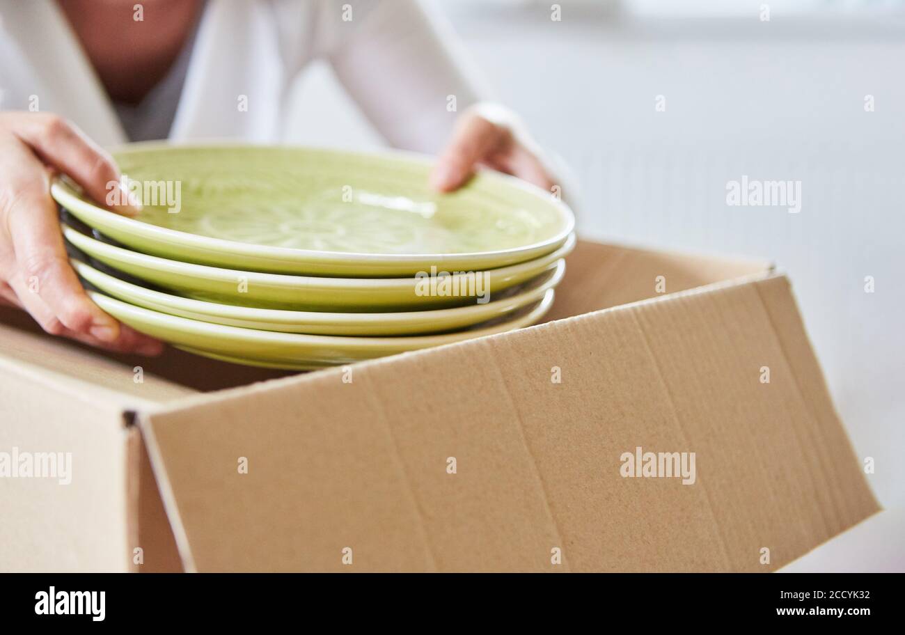 Woman packs plates in a moving box when moving to a new home Stock ...