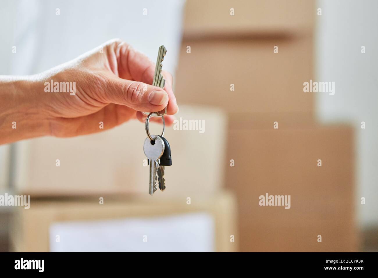 Hand of owner is holding a key as a symbol of house purchase and ...