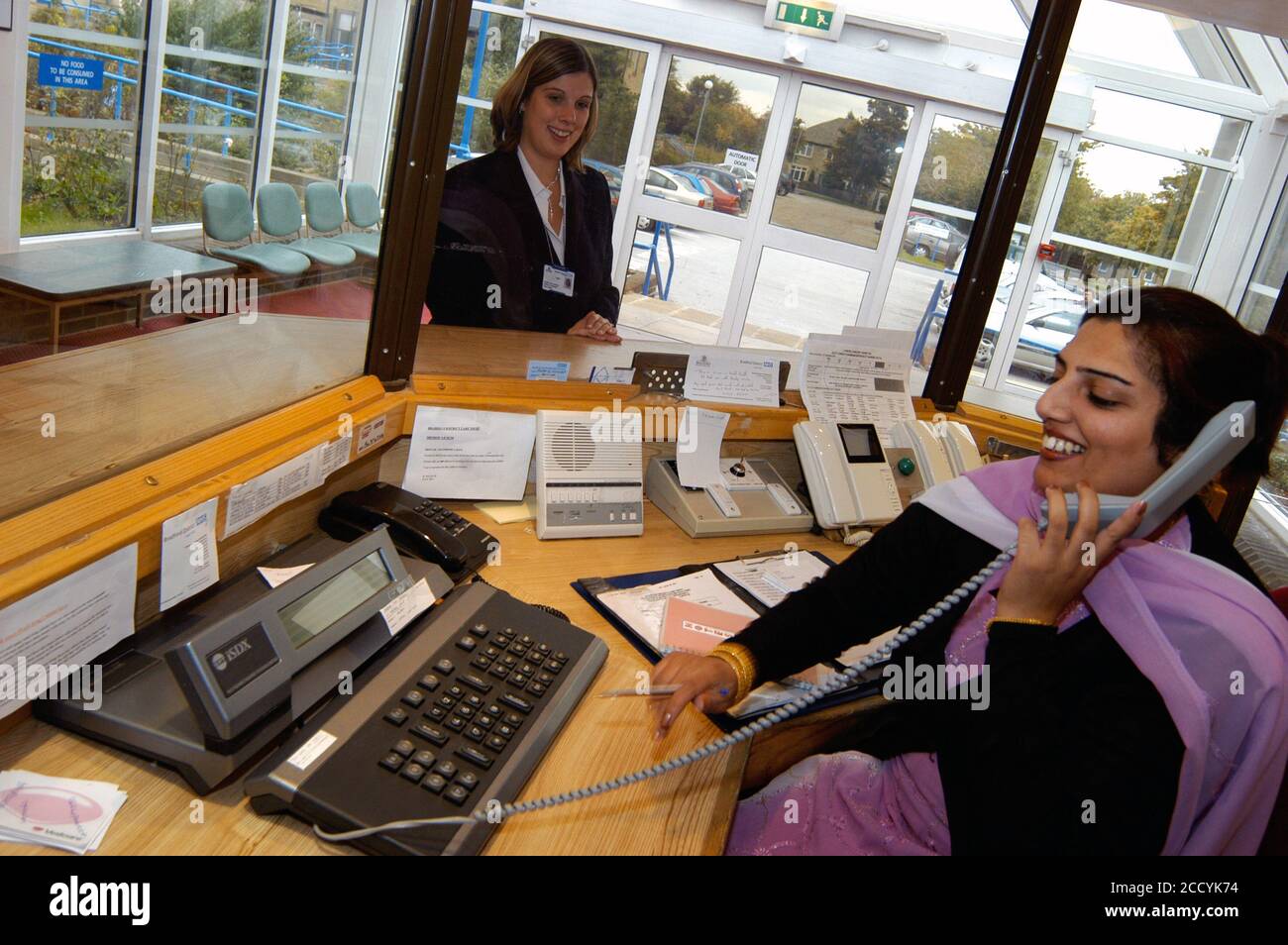 Receptionist on phone at work in NHS hospital Bradford Yorkshire UK ...