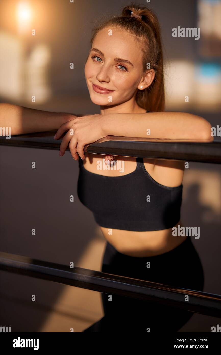Attractive young female gymnast stands smiling kindly in gymnastics ...