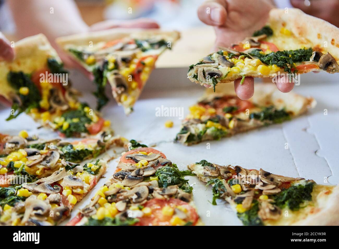 Friends eating vegetarian vegetable pizza together from a pizza box ...