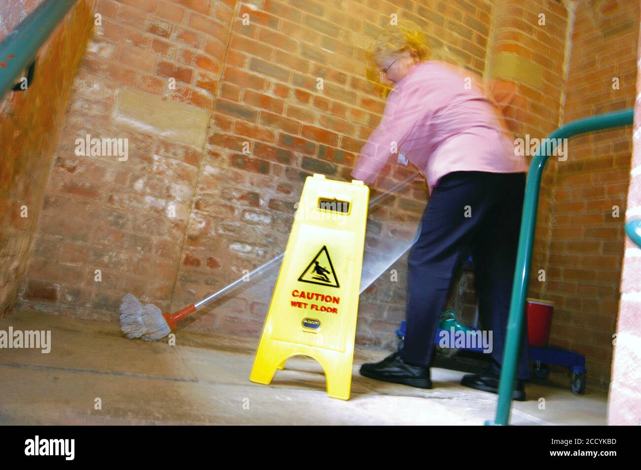 Cleaner mops the floor with health & safety warning sign in NHS ...