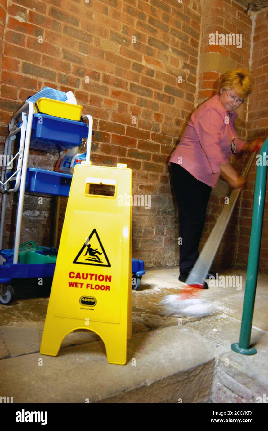 Cleaner mops the floor with health & safety warning sign in NHS ...