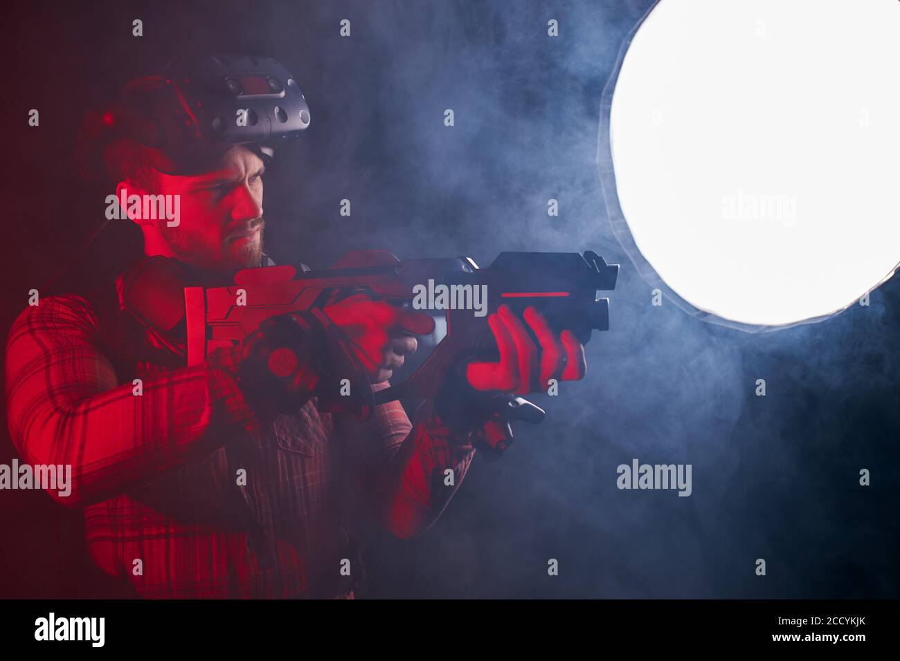 Young man holding virtual reality gun, ready to shoot. Studio shoot ...