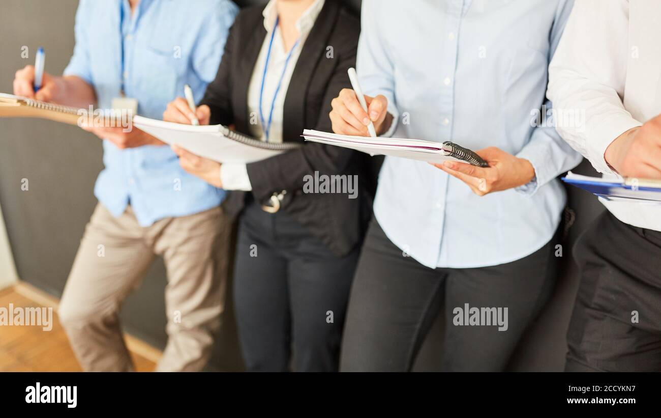 Group of business people making notes with pen and writing pad while ...