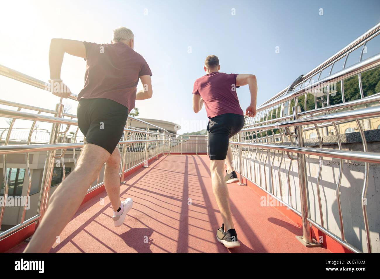 Back view of yound male and mature grey-haired male running across the ...