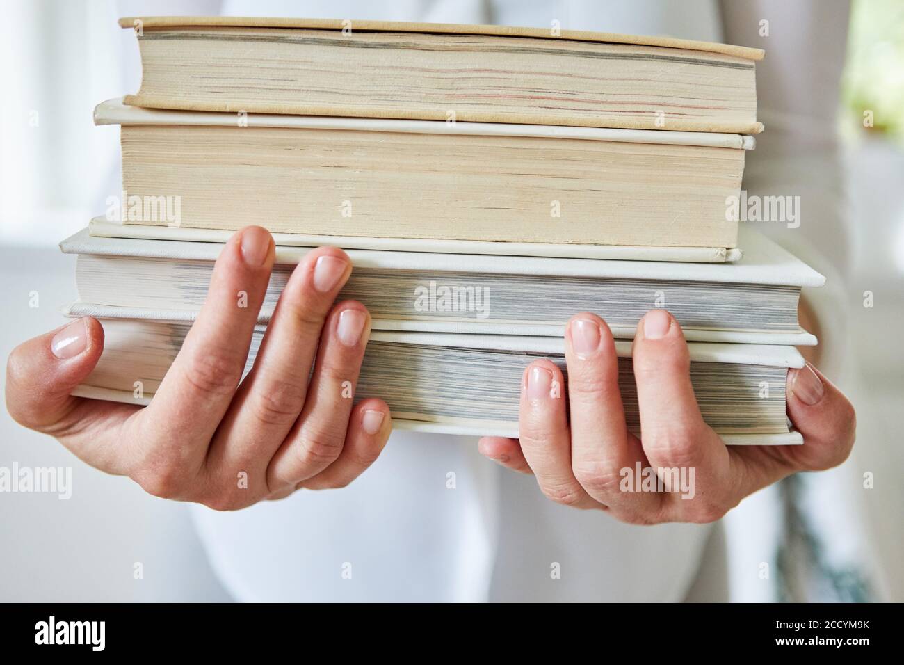 Woman carries stack of old books in her arms with hands Stock Photo - Alamy