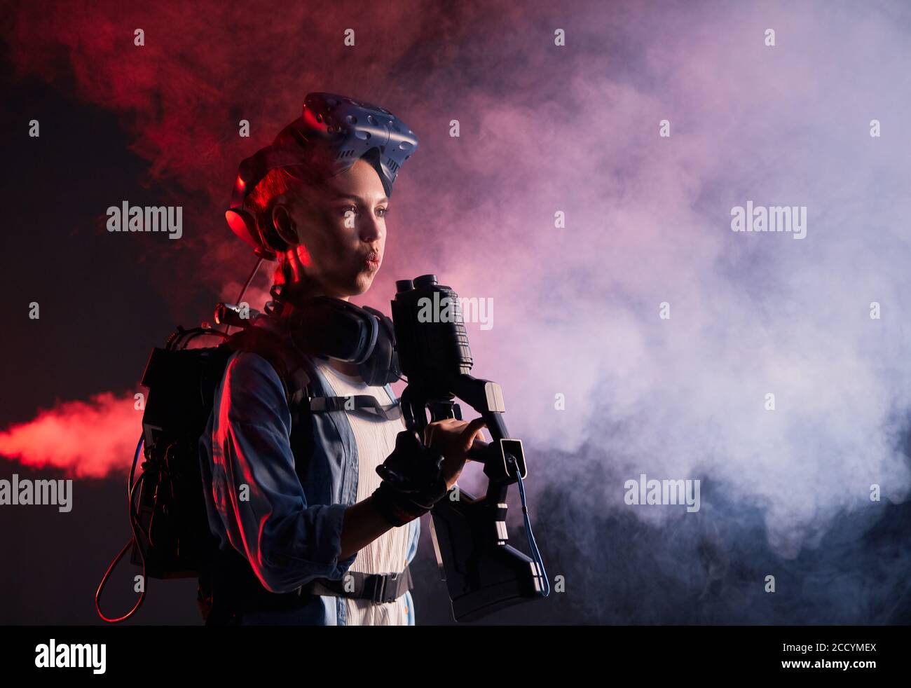 Beautiful girl playing virtual game, stand blowing the barrel of vr ...