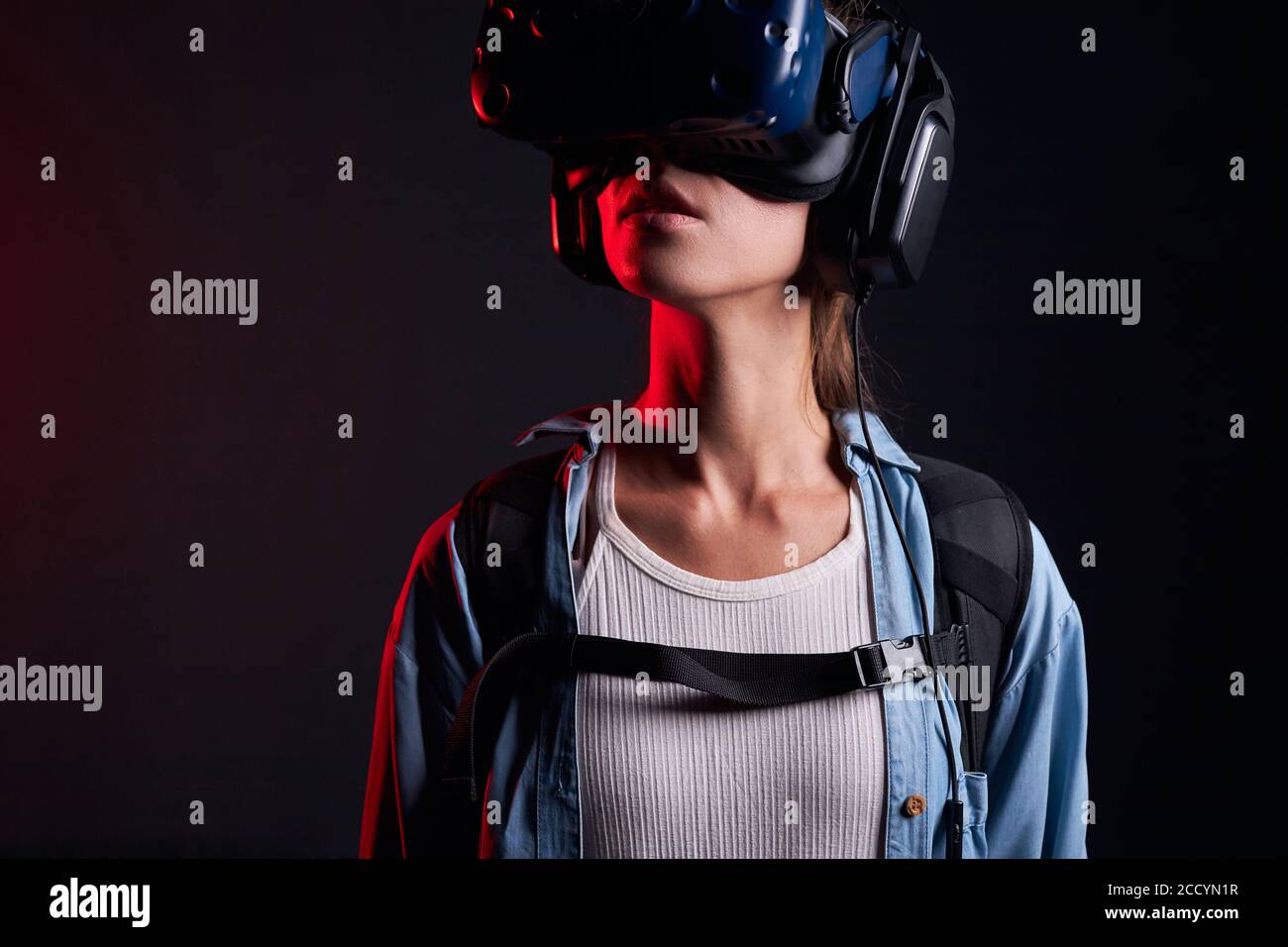 Portrait of young girl wearing VR device on eyes. Isolated over black ...